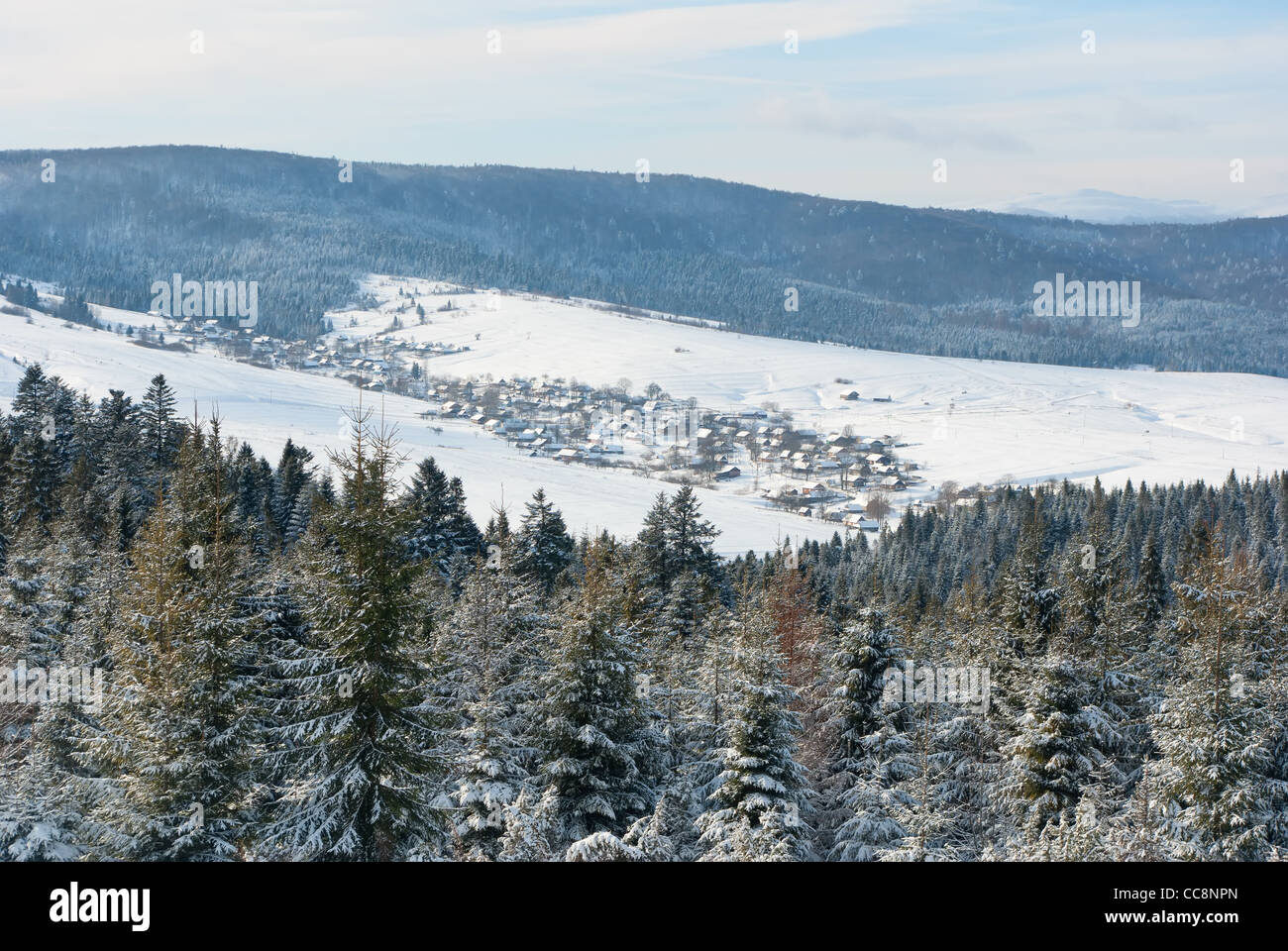 snow village in valley between winter mountains with fir tree forest in ...