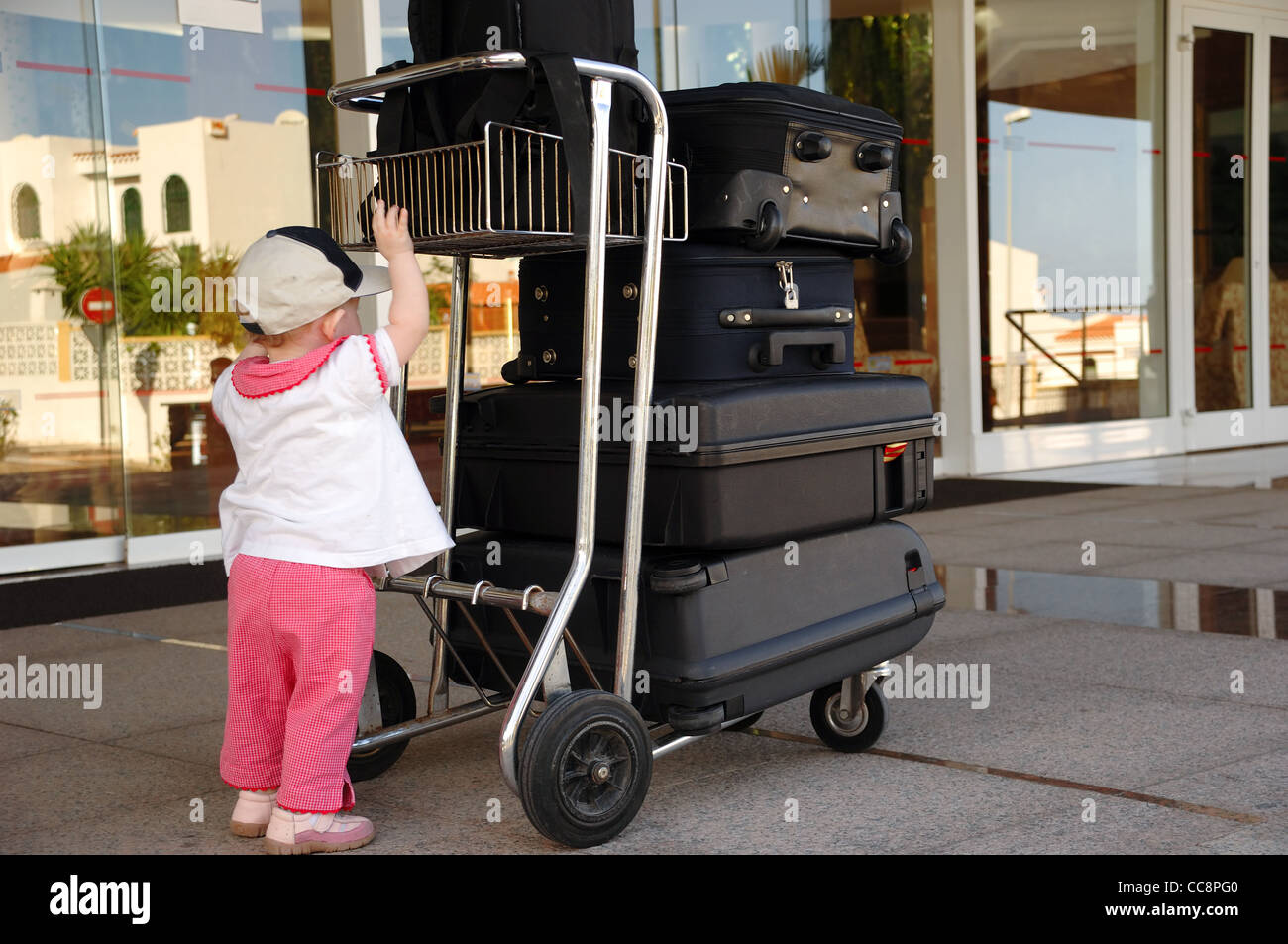 Young child is trying to push the a cart with many suitcases Stock ...