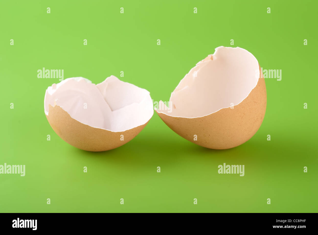 Two pieces of brown egg shell on a green background Stock Photo - Alamy