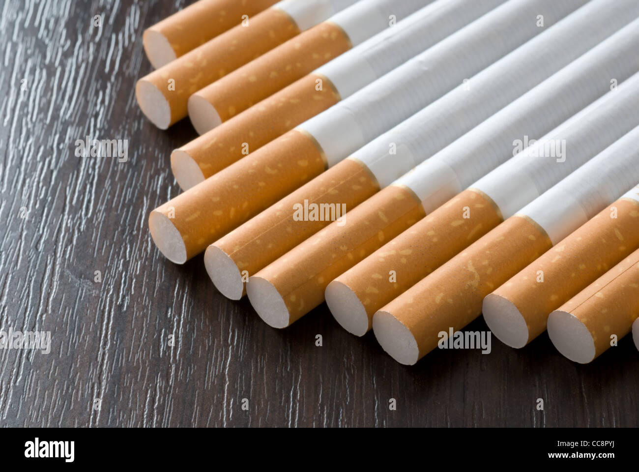 Three cigarettes on the black wooden table Stock Photo - Alamy
