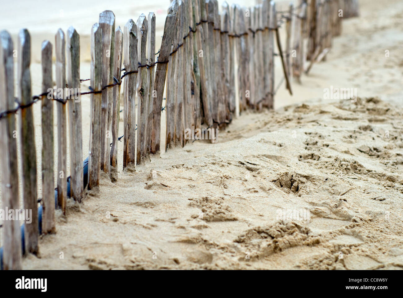 A wooden fence topped with barb wire on a sandy beach Stock Photo - Alamy