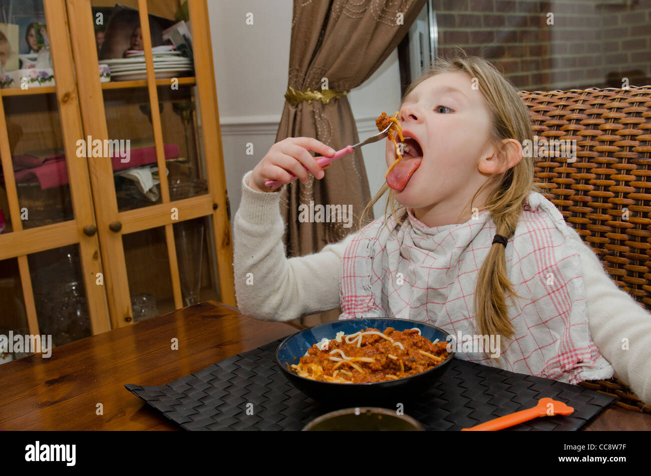 A young child girl enjoying eating a bowl of spaghetti bolognaise ...
