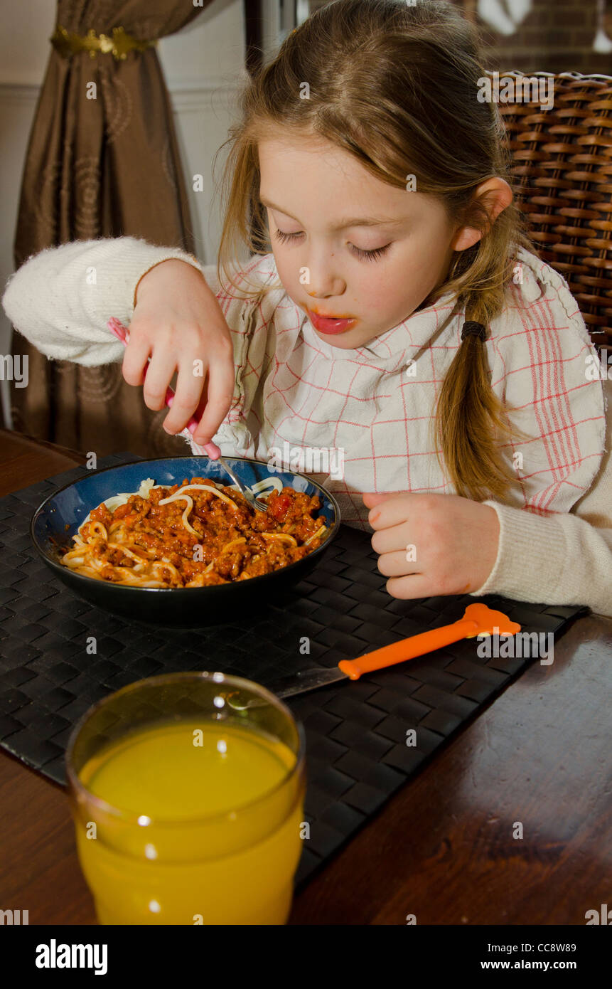 A young child girl enjoying eating a bowl of spaghetti bolognaise ...