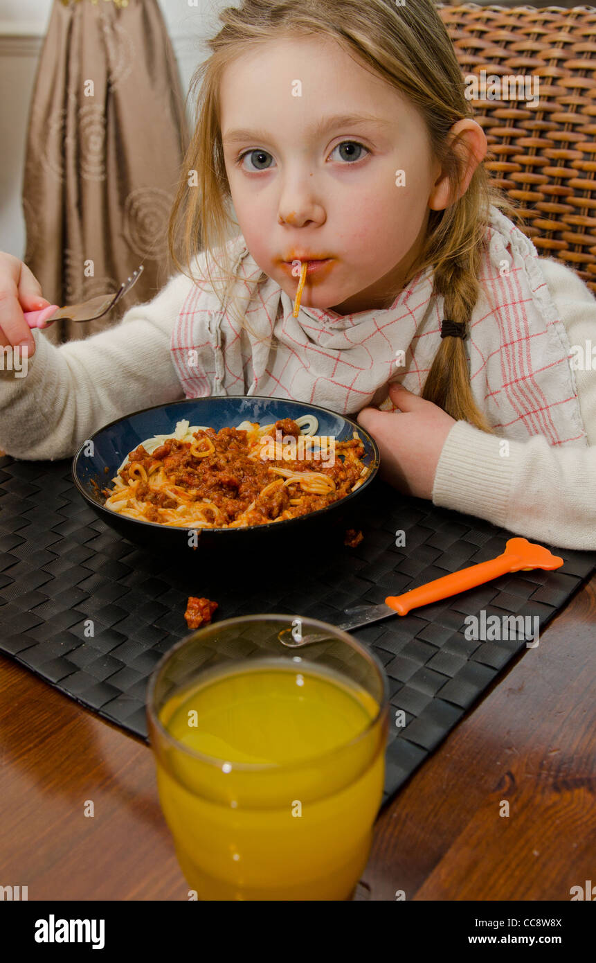 A young child girl enjoying eating a bowl of spaghetti bolognaise ...