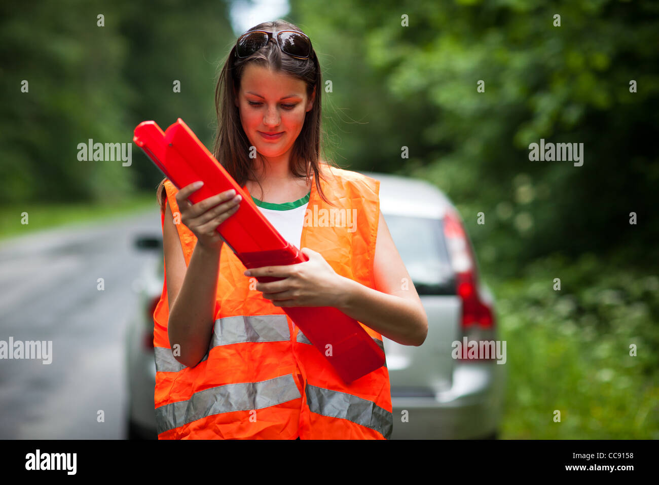 Young female driver wearing a high visibility vest after her car has ...