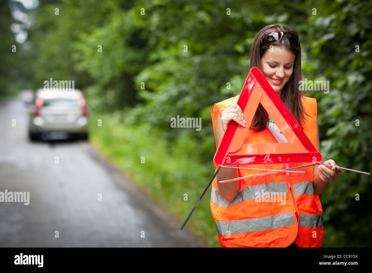 Young female driver wearing a high visibility vest after her car has ...