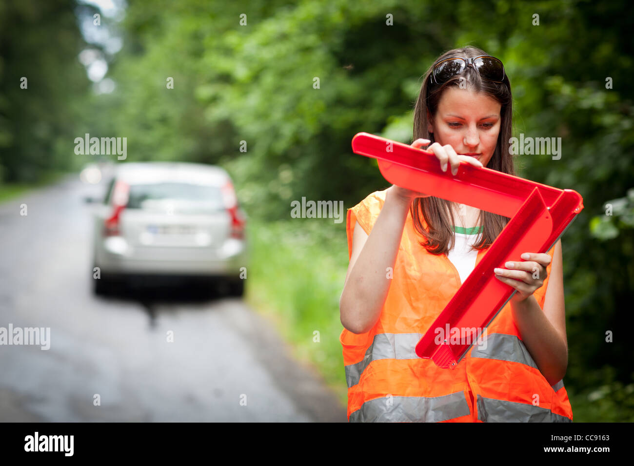 Young female driver wearing a high visibility vest after her car has ...