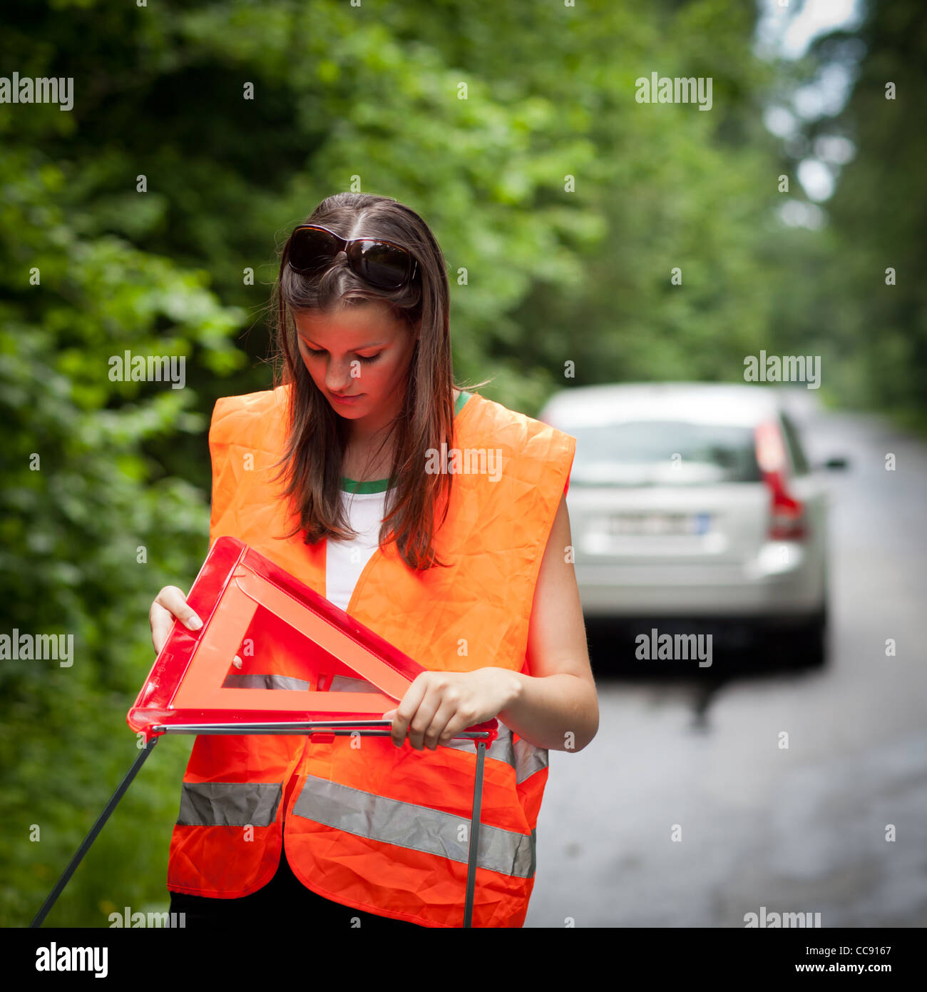 Young female driver wearing a high visibility vest after her car has ...