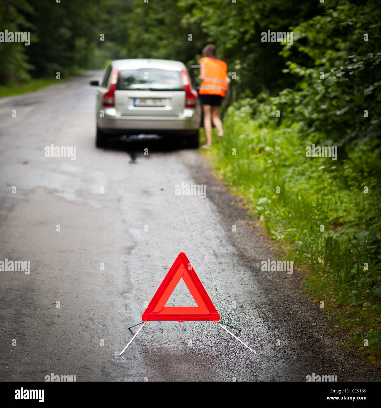 Young female driver wearing a high visibility vest after her car has ...