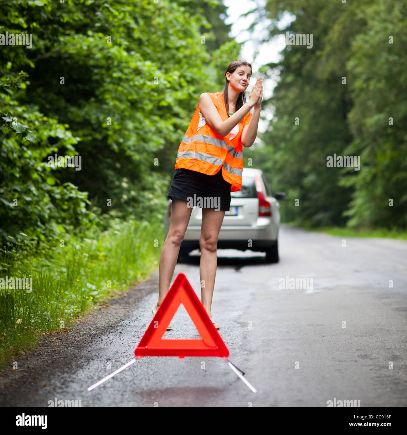 Young female driver wearing a high visibility vest, calling the ...