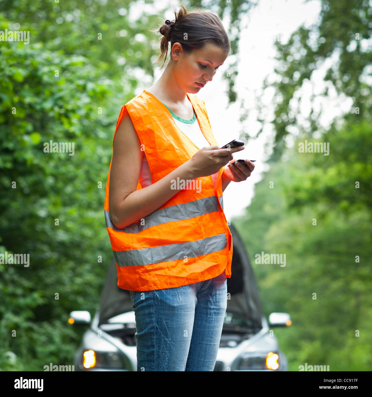 Young female driver wearing a high visibility vest, calling the ...