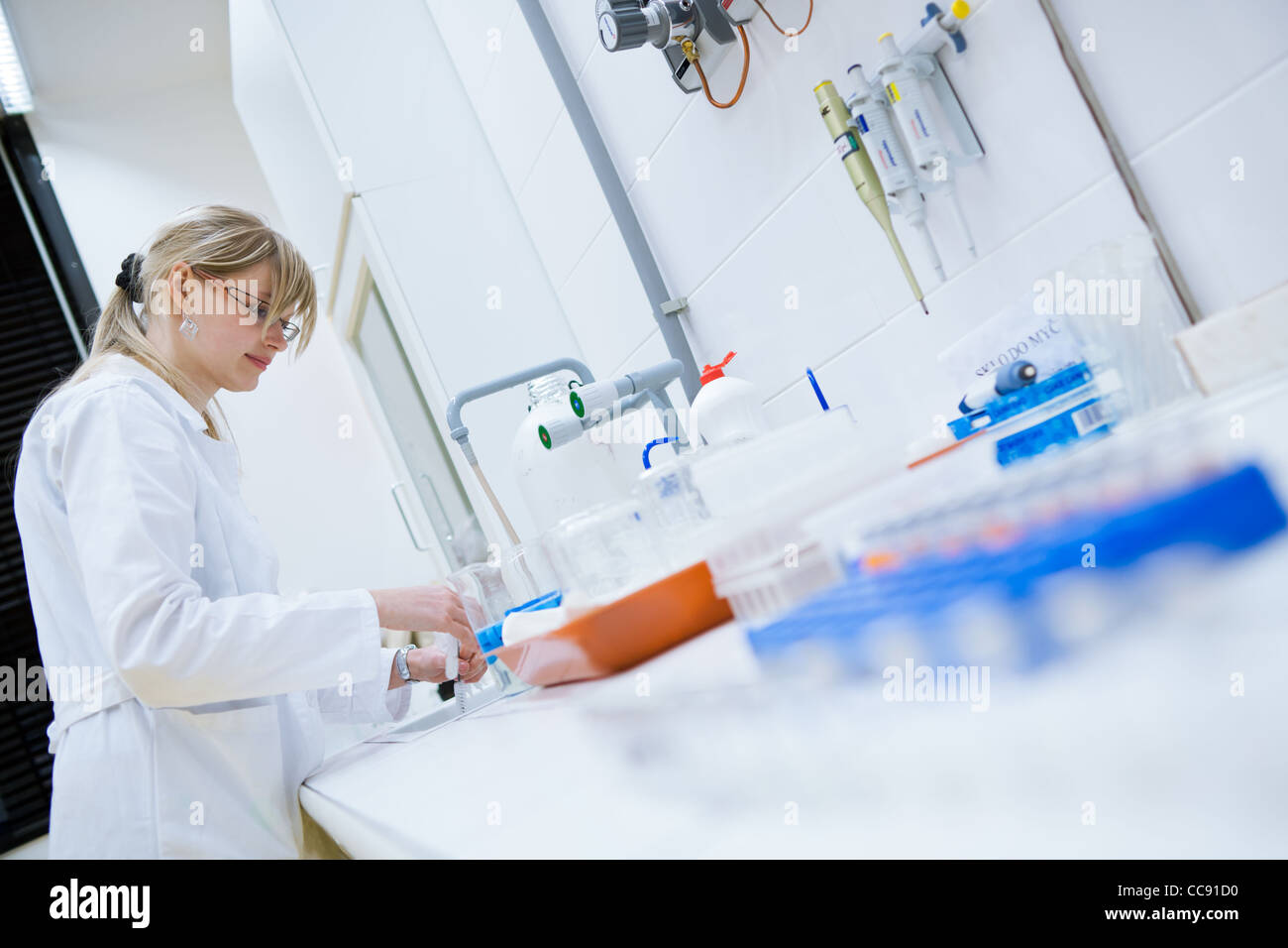 female researcher carrying out research experiments in a chemistry lab ...