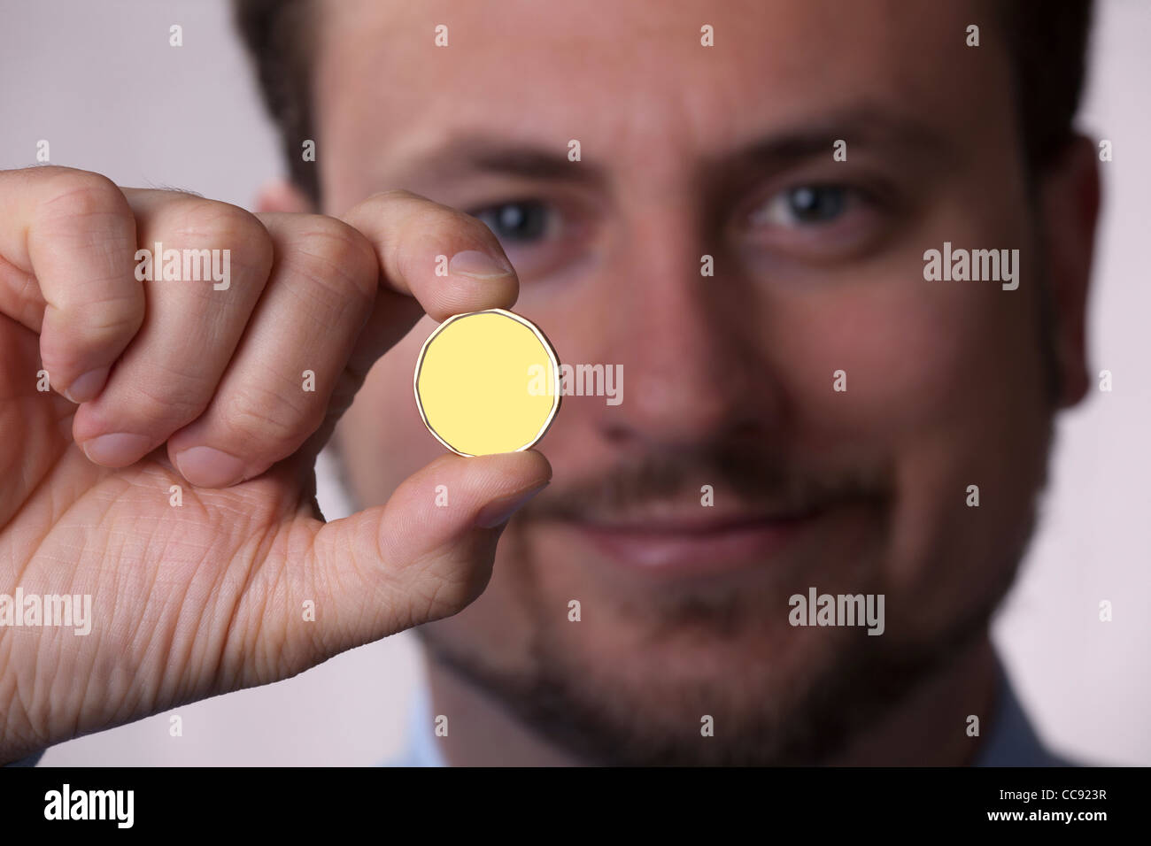 Smiling man holding a gold coin Stock Photo - Alamy