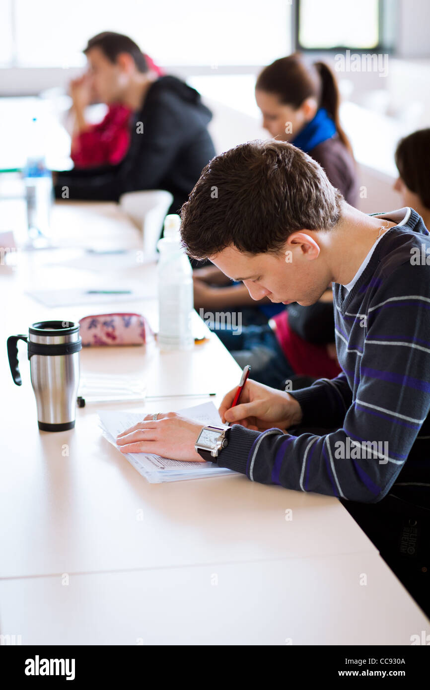 young, handsome male college student sitting in a classroom full of ...
