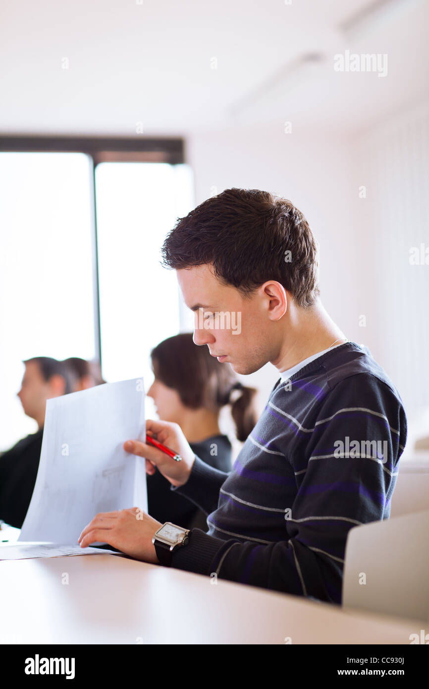 young, handsome male college student sitting in a classroom full of ...