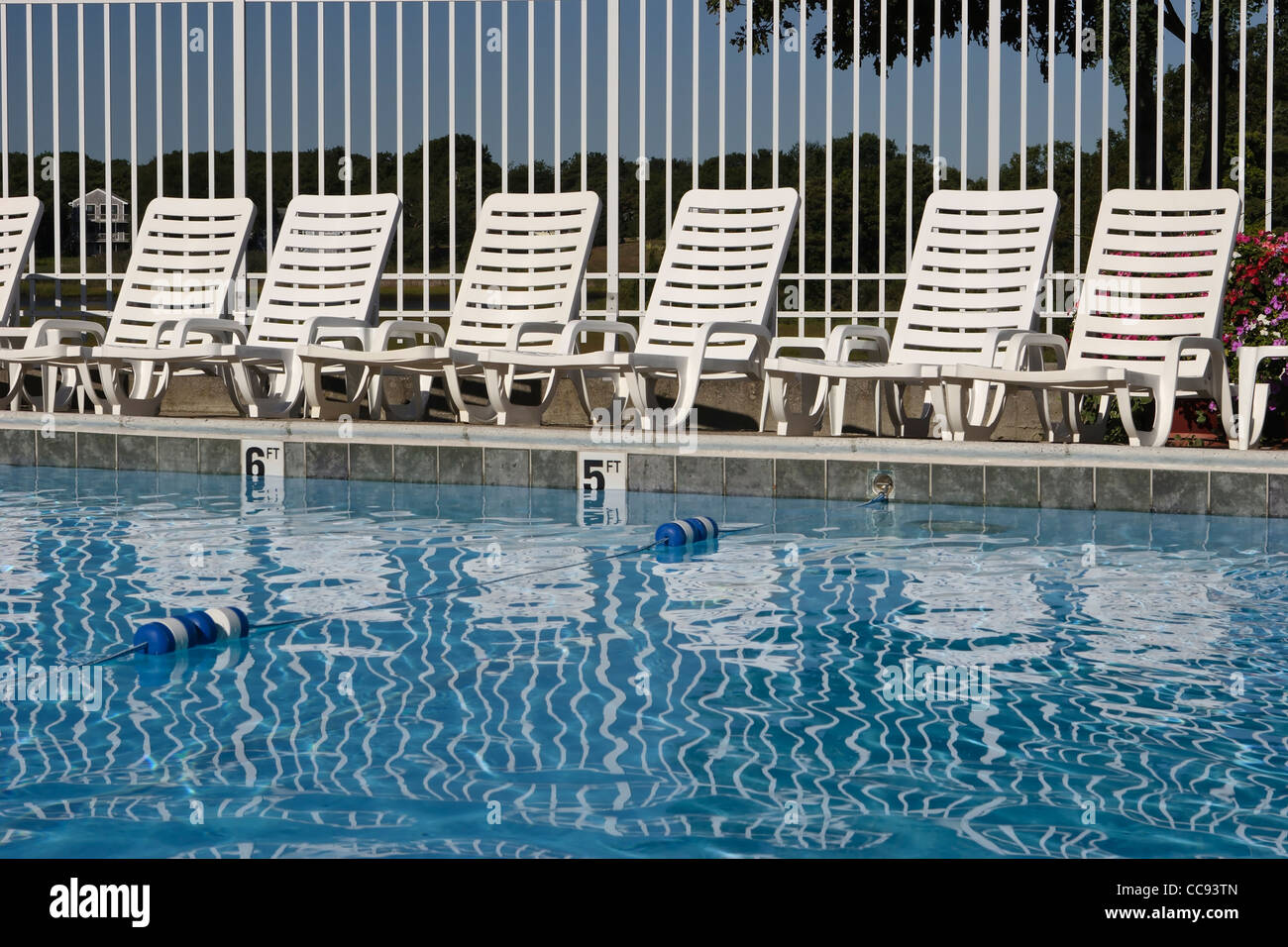 Empty lounge chairs by outdoor swimming pool Stock Photo - Alamy