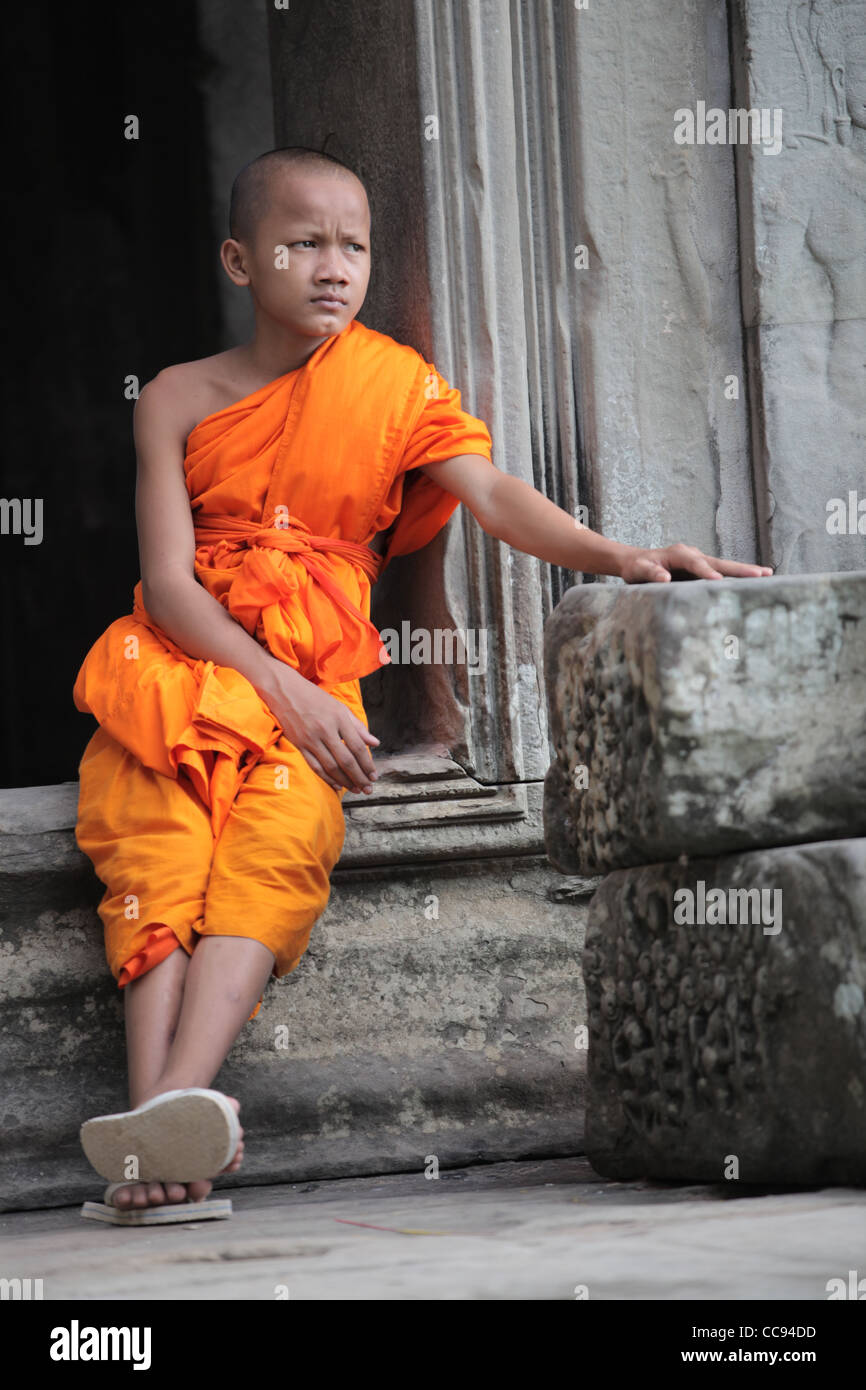An apprentice monk looking out from the ruins of Angkor Wat in Cambodia ...