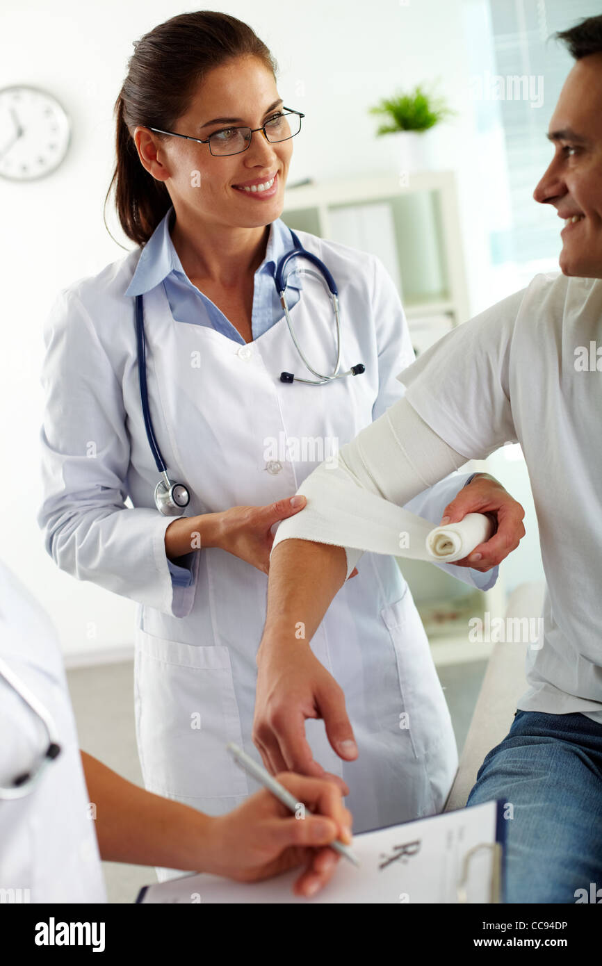 Portrait of pretty female doctor giving first aid to patient in ...