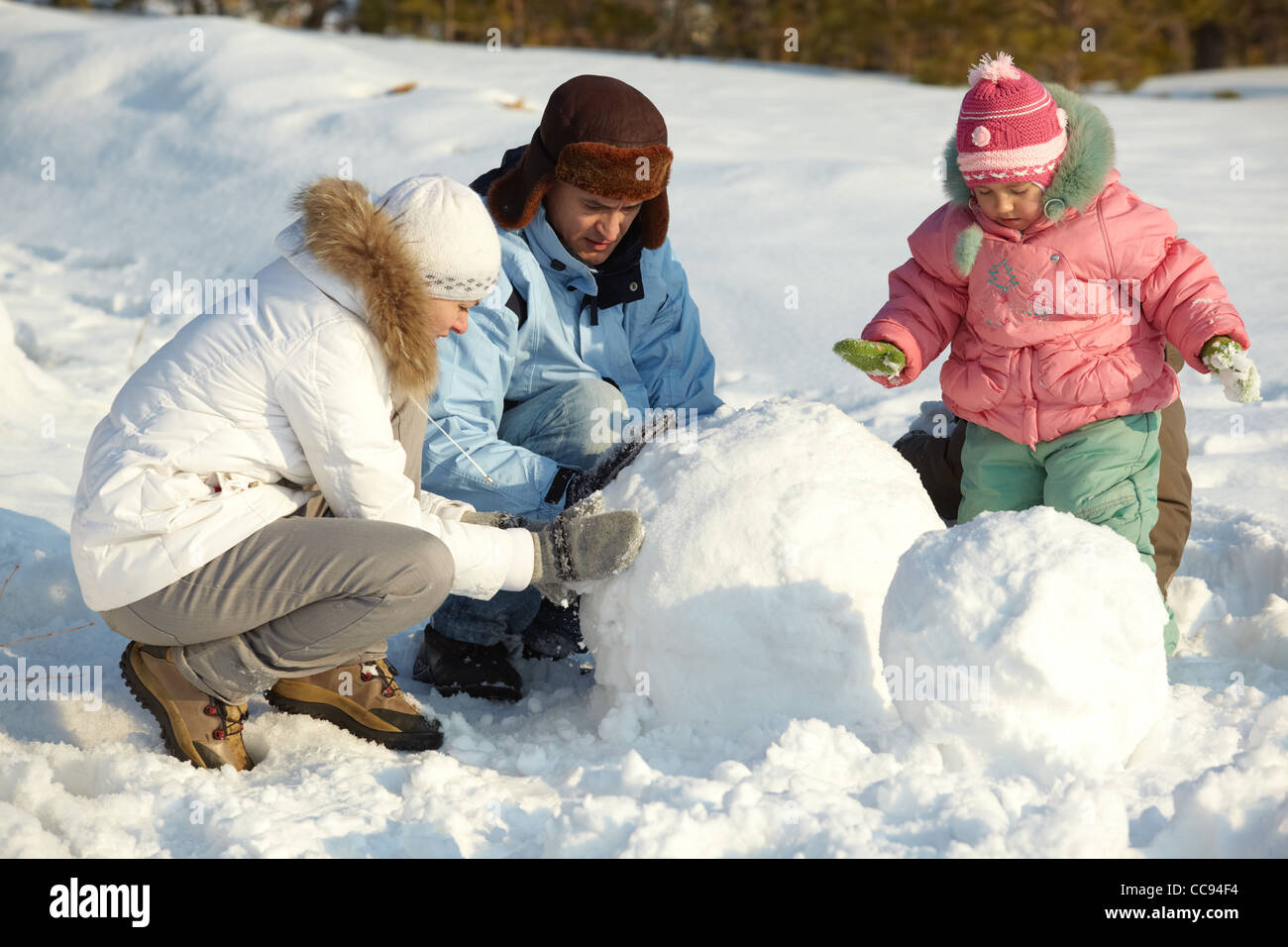 Portrait of family making snowman in park Stock Photo - Alamy