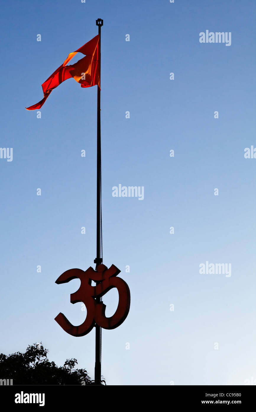 Silhouette of trees and Hindu Om sign, flag pole and saffron flag fly ...