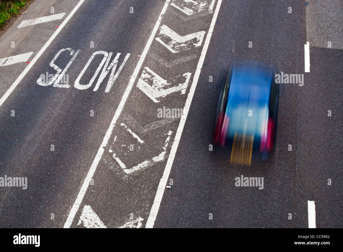 Car driving one a road with a "Slow" marking in the left hand lane ...