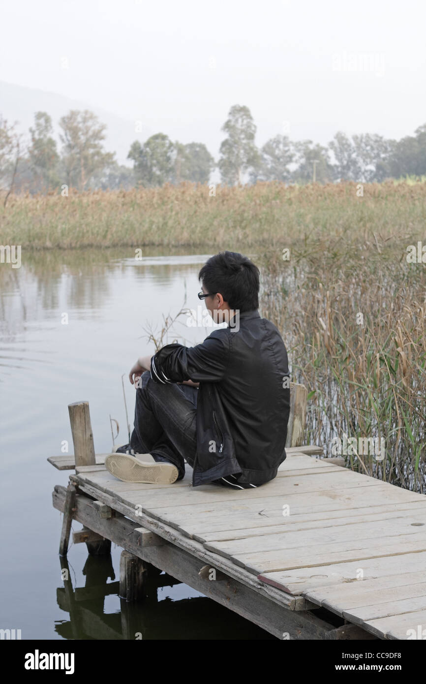 man sitting on a wooden pier Stock Photo - Alamy