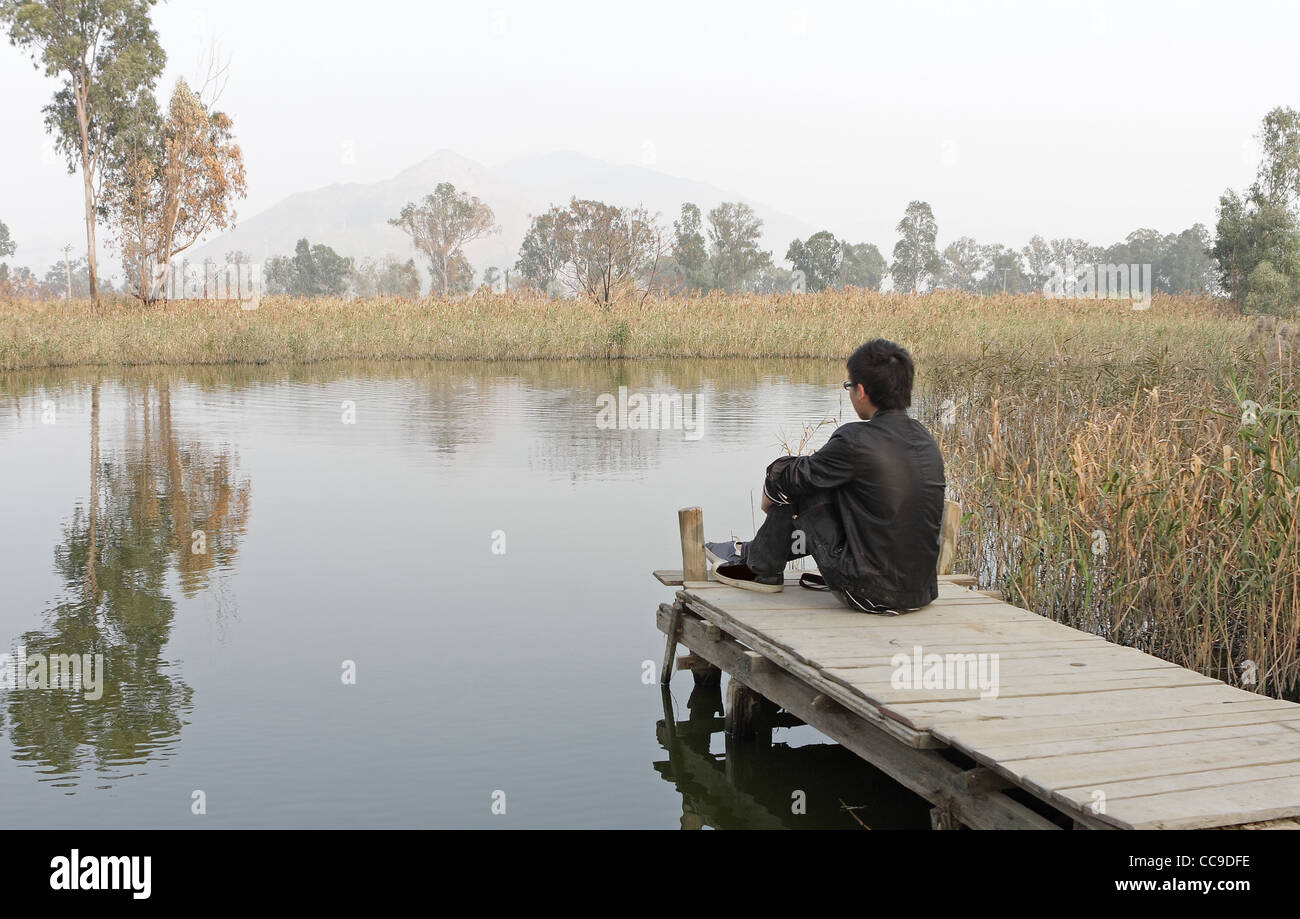man sitting on a wooden pier Stock Photo - Alamy
