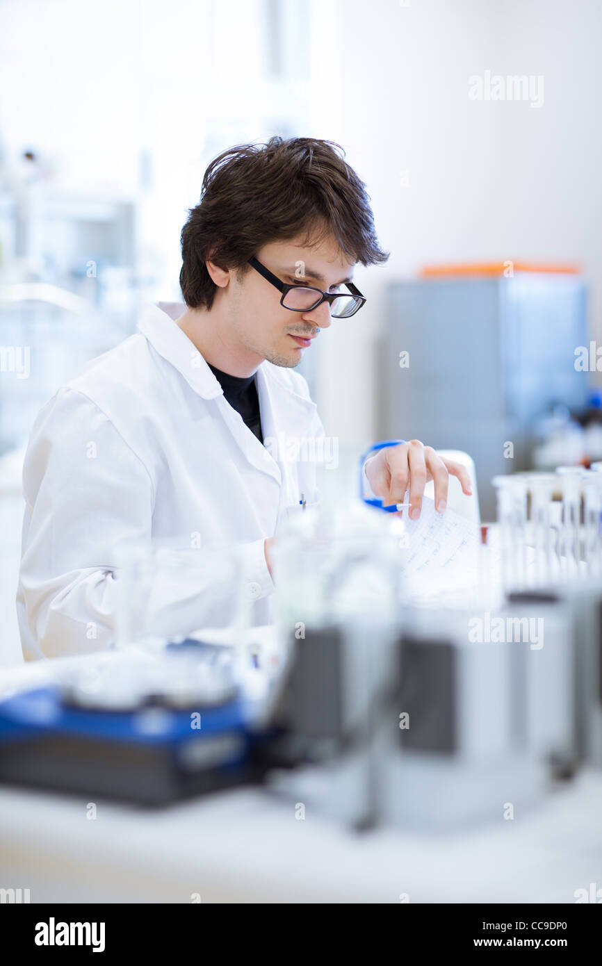 young, male researcher/chemistry student carrying out scientific ...