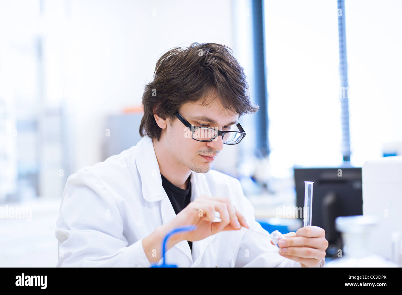young, male researcher/chemistry student carrying out scientific ...