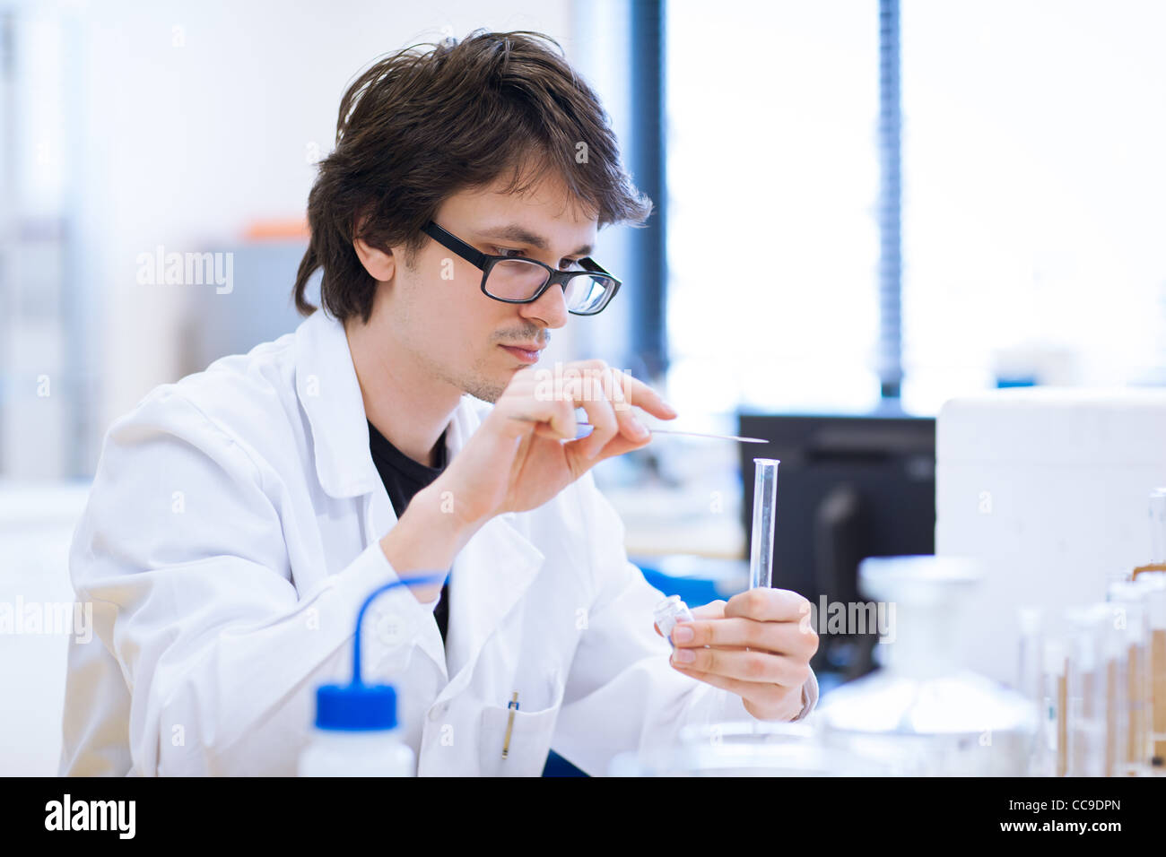 young, male researcher/chemistry student carrying out scientific ...