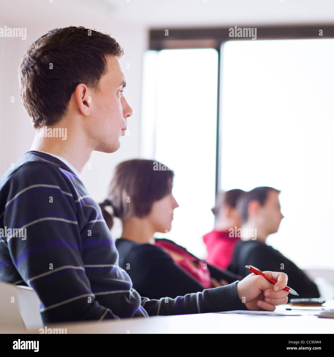 handsome young male college student sitting in a classroom full of ...