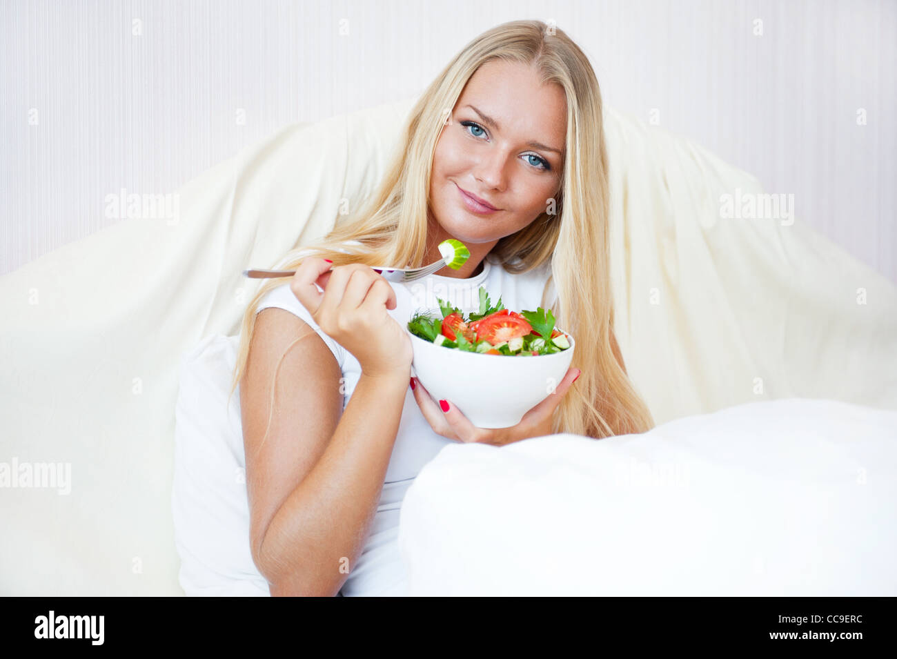 Closeup Portrait of a beautiful slender girl eating healthy food at bed ...