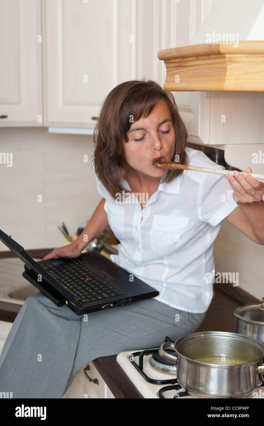 Multitasking woman - cooking meal and working Stock Photo - Alamy