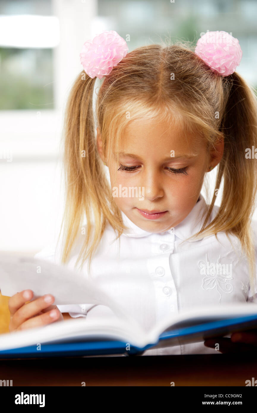 Image of smart child reading interesting book in classroom. Vertical ...