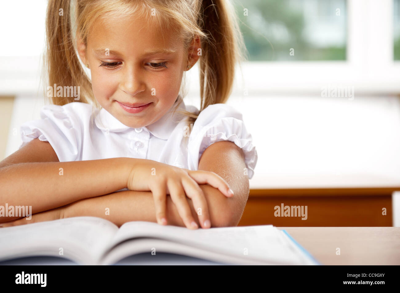 Image of smart child reading interesting book in classroom. Horizontal ...