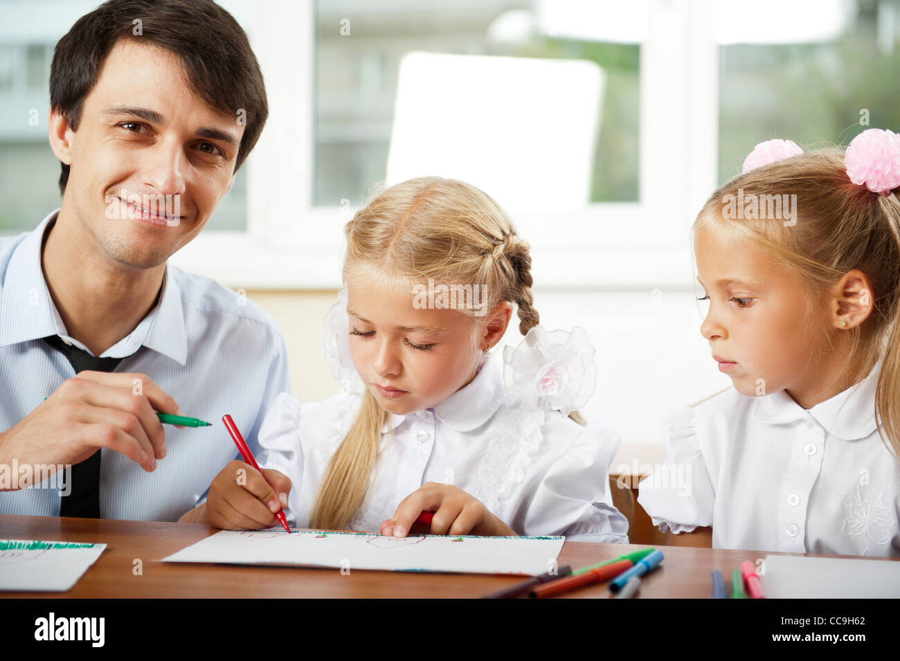 Teacher helping elementary school pupils with their tasks Stock Photo ...