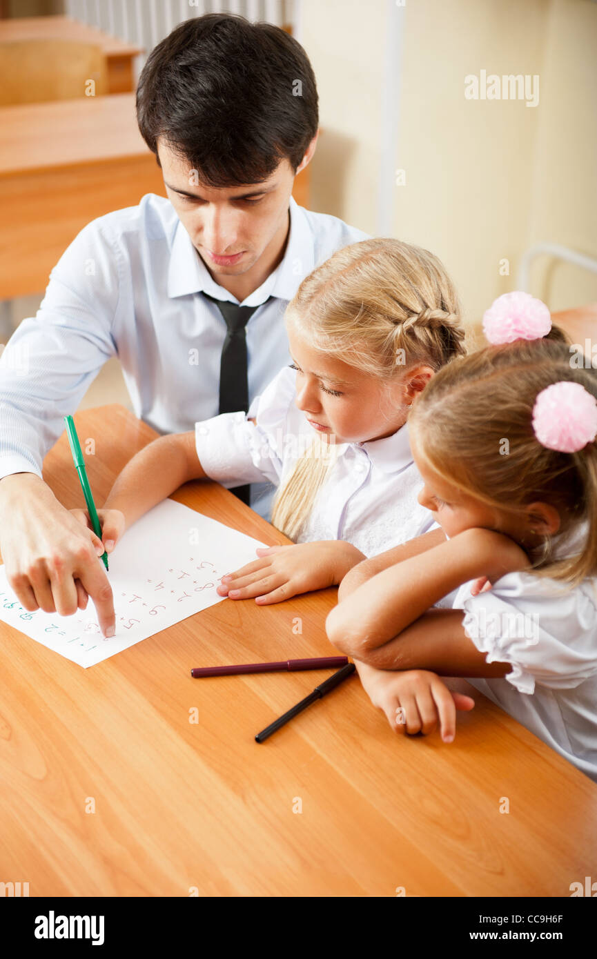Teacher helping elementary school pupils with their tasks Stock Photo ...