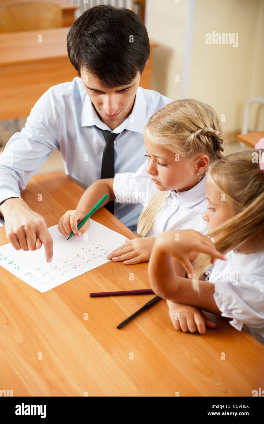 Teacher helping elementary school pupils with their tasks Stock Photo ...