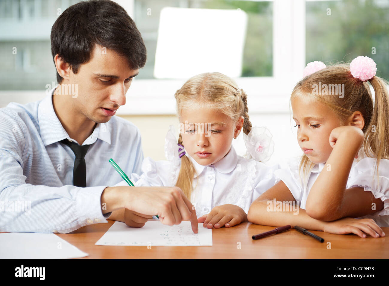 Teacher helping elementary school pupils with their tasks Stock Photo ...