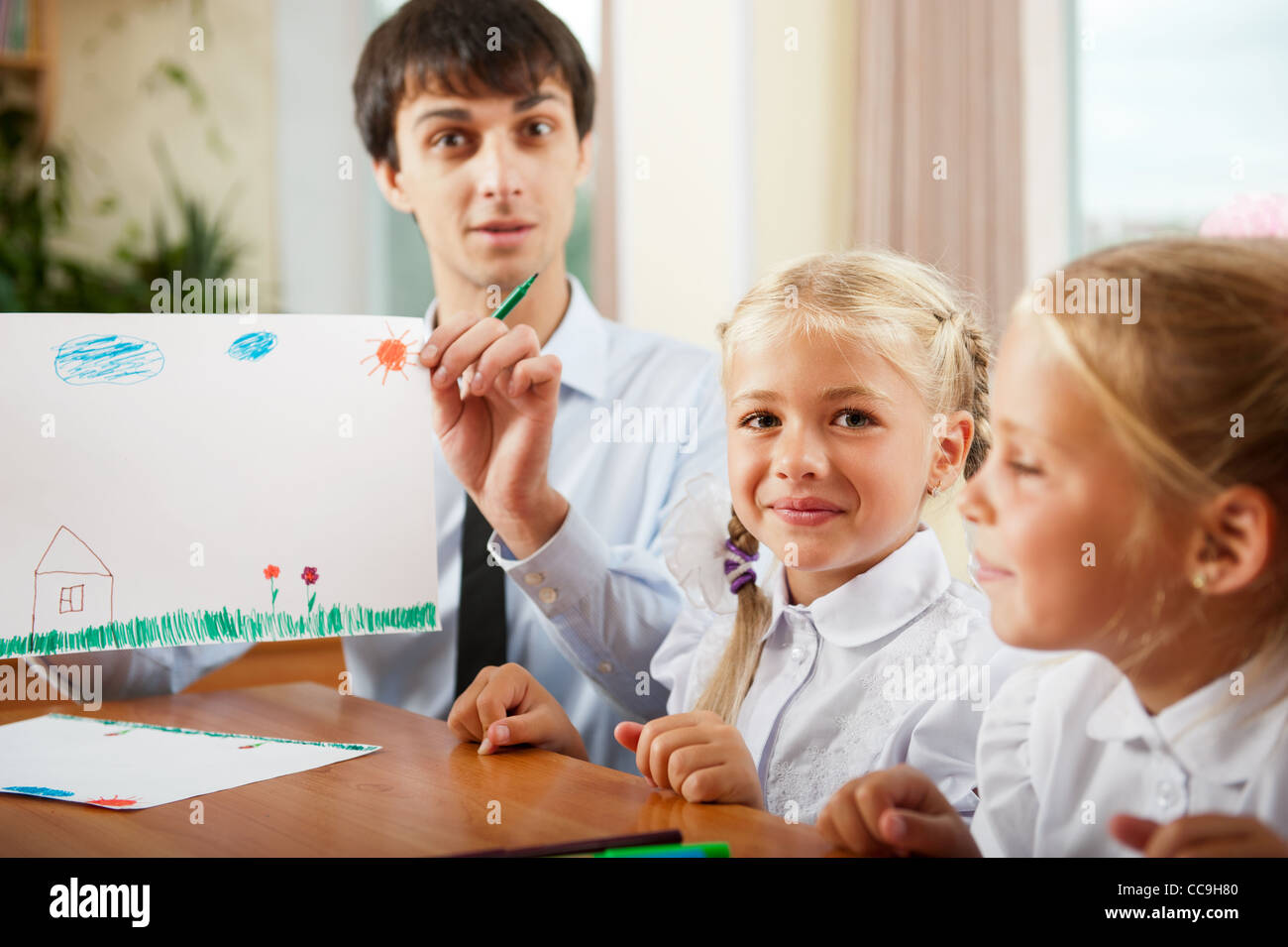 Teacher helping students with schoolwork in school classroom ...
