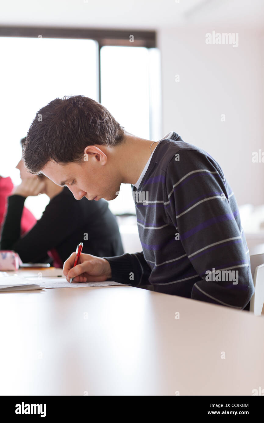 young, handsome male college student sitting in a classroom full of ...