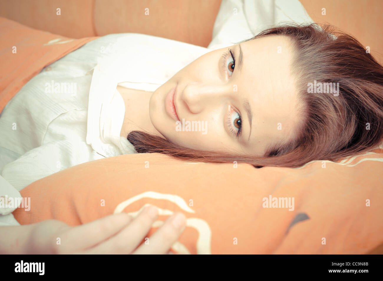 Closeup Portrait of young pretty girl laying on her bed at her modern ...