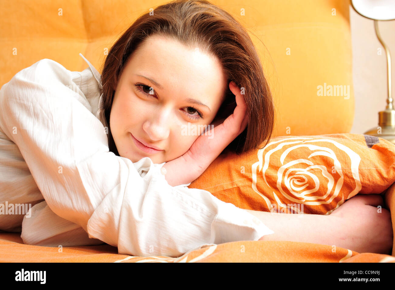 Closeup Portrait of young pretty girl laying on her bed at her modern ...