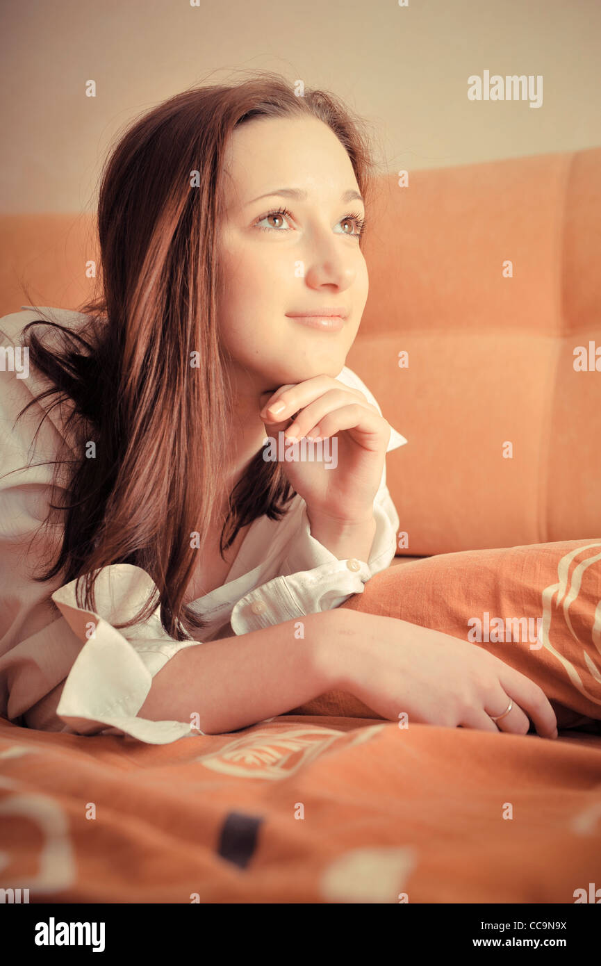 Closeup portrait of young pretty girl laying on her bed at her modern ...