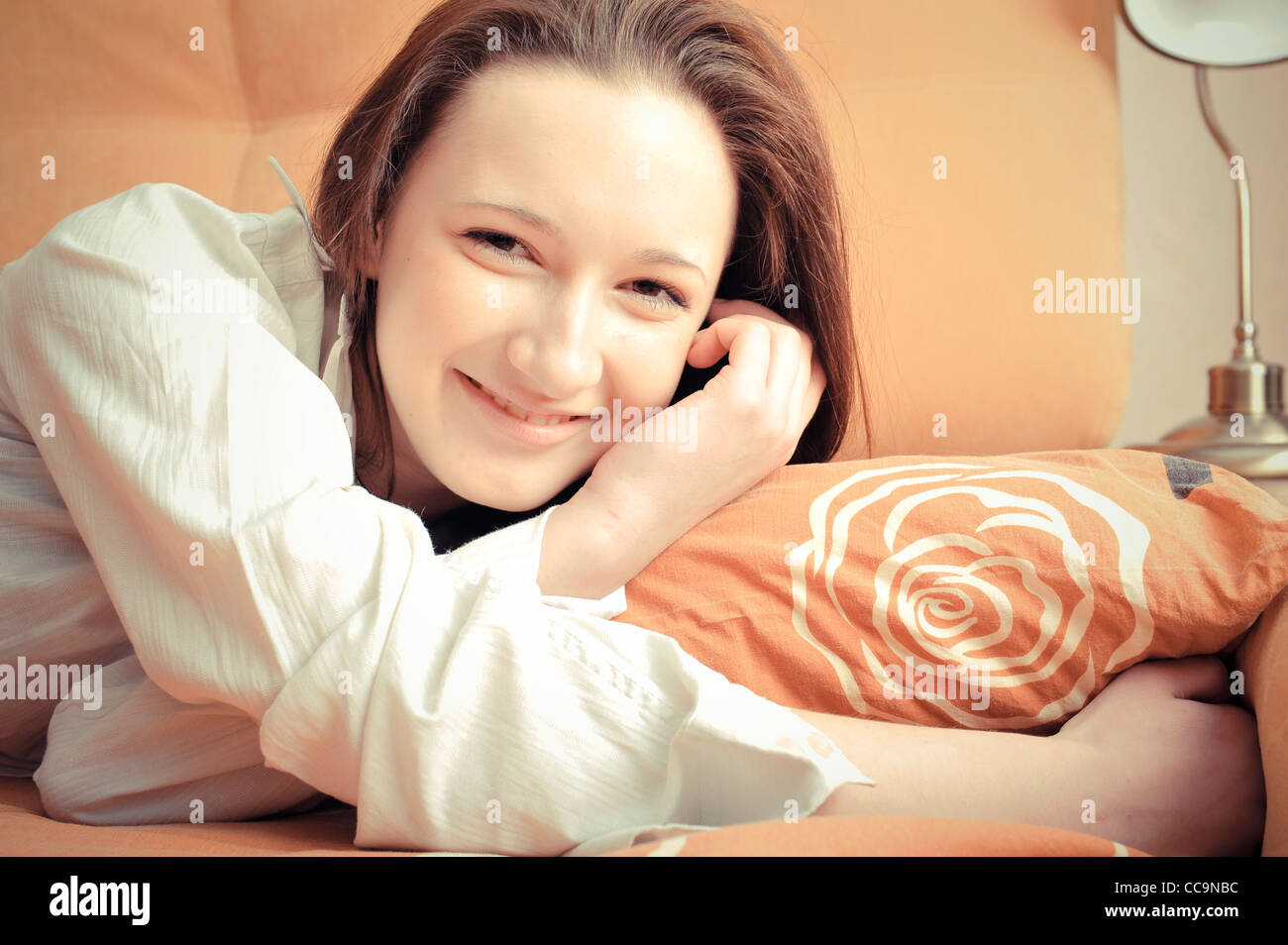 Closeup portrait of young pretty girl laying on her bed at her modern ...
