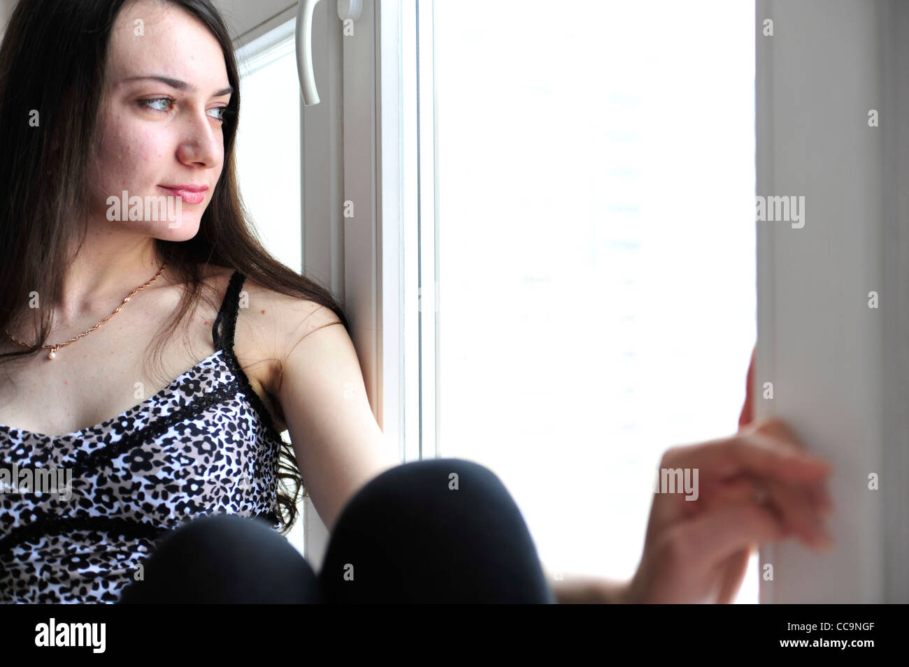 Young woman at home sitting near the window and looking Stock Photo - Alamy