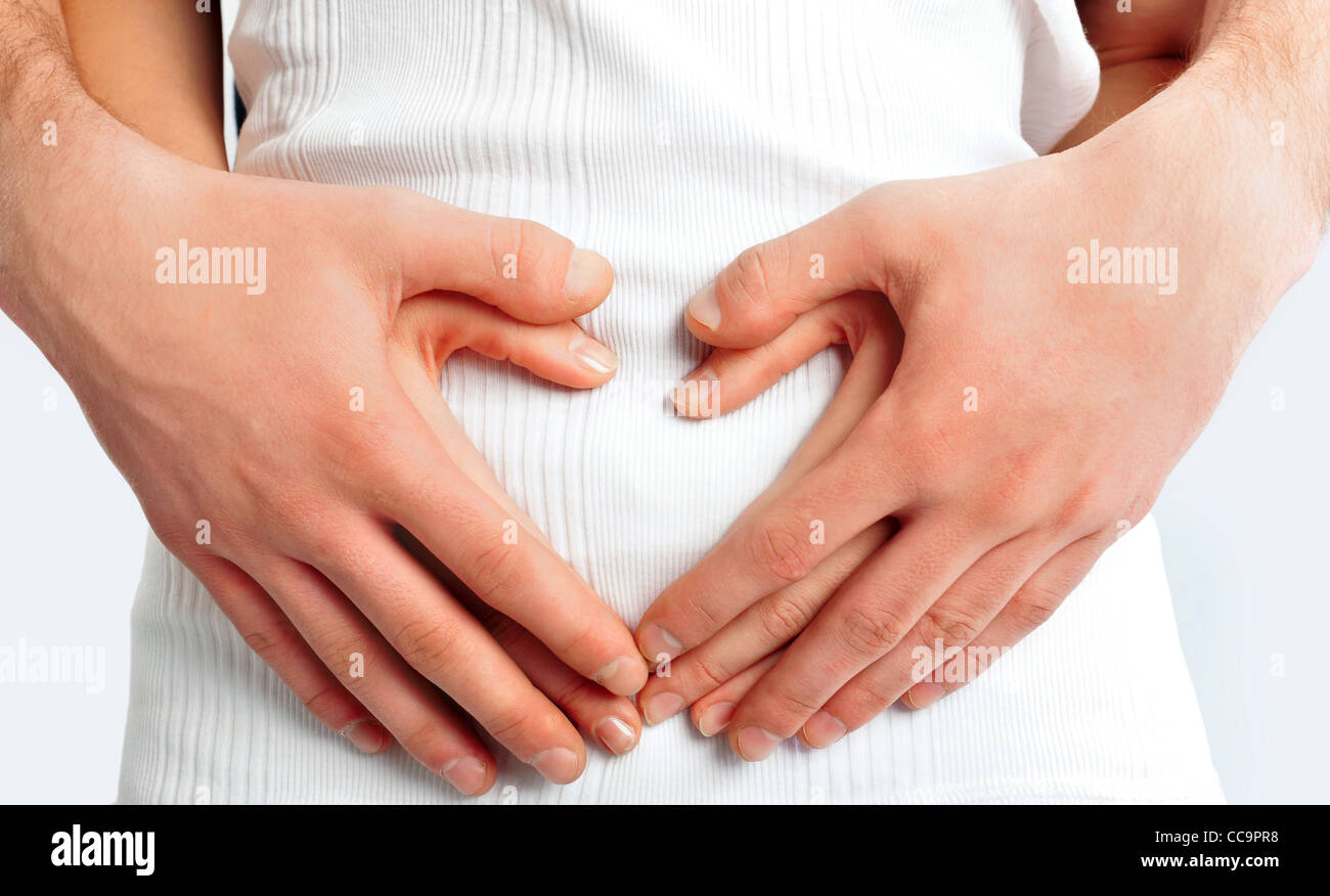 Pregnant women wrap her arms around the belly in the form of the heart ...