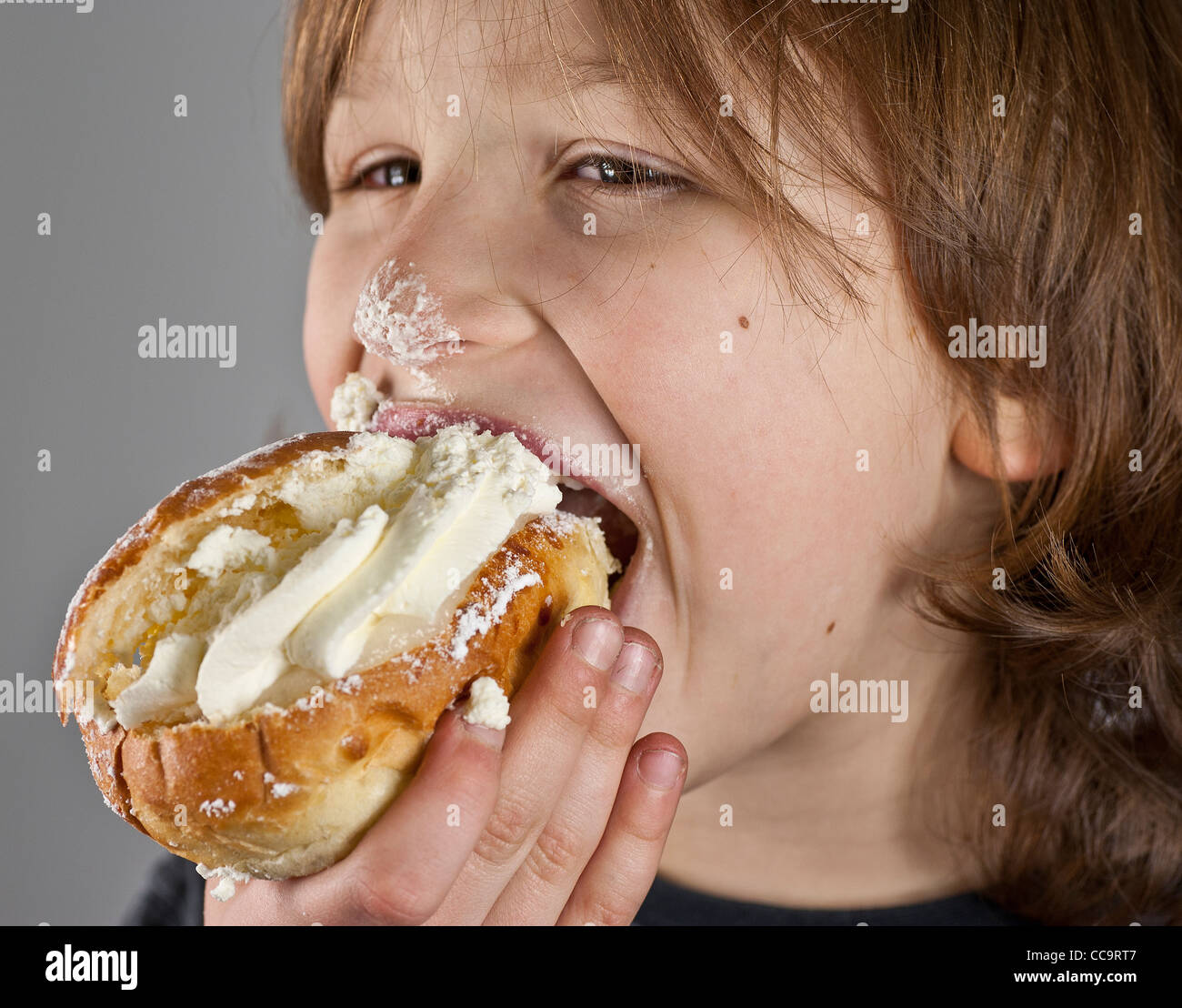 Young boy enjoying a cream bun with almond paste Stock Photo - Alamy