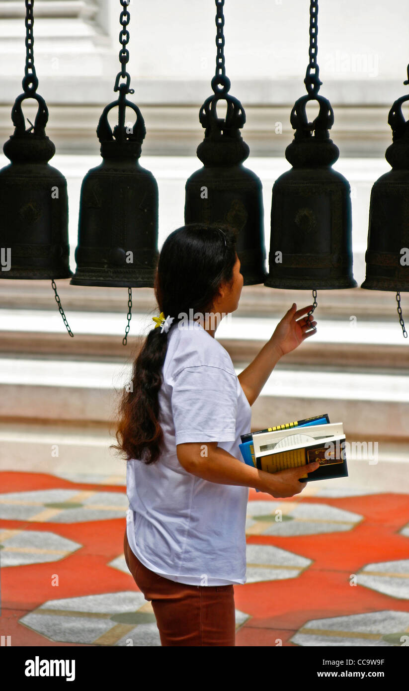 A woman rings Buddhist's bells inside a temple in Bangkok, Thailand ...