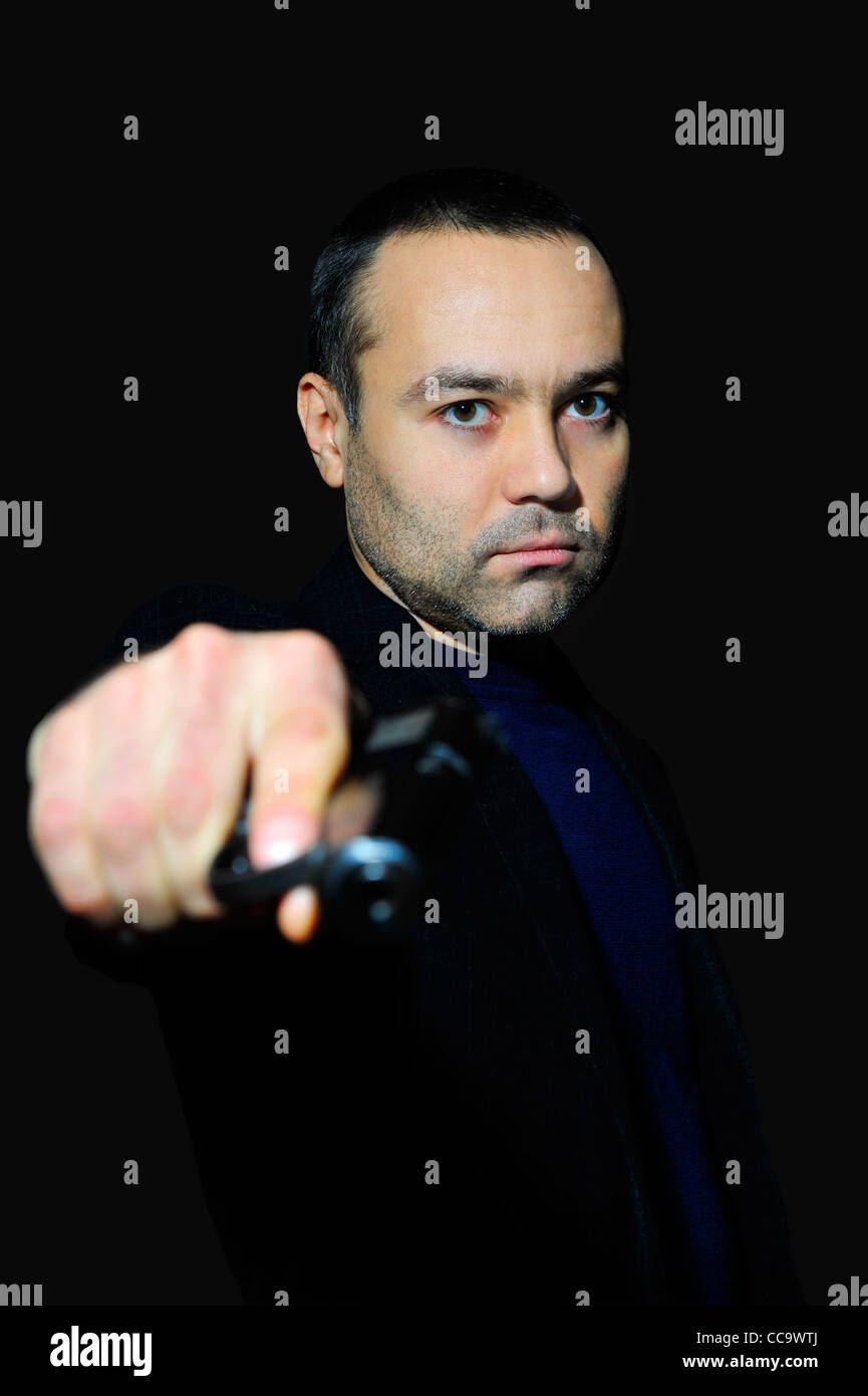 Portrait of a mature man drawing a gun in self defense studio shoot ...